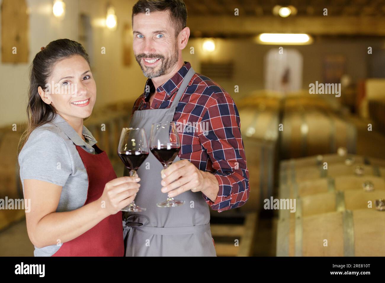 glad professional team of winery posing with wine in cellar Stock Photo ...