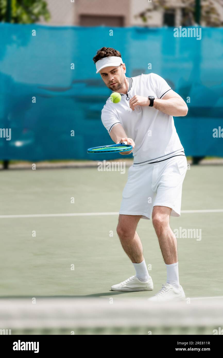 bouncing tennis ball, handsome tennis player practicing on court ...
