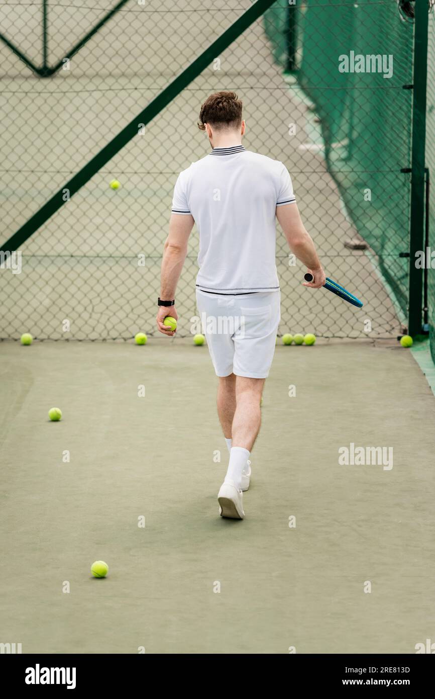 male player with tennis racket walking around balls on court, hobby and ...