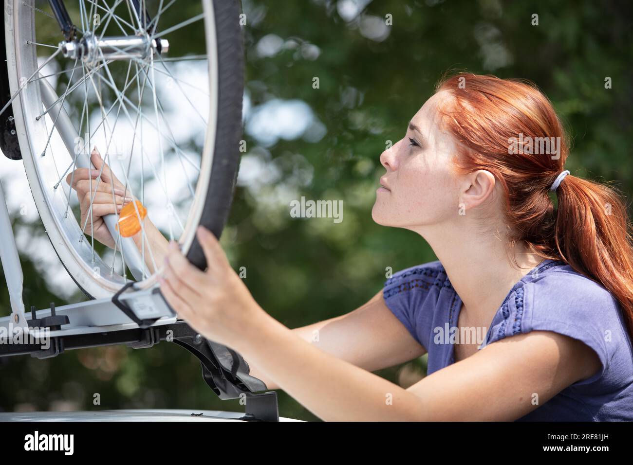 female cyclist taking mountain bike from rack on car Stock Photo - Alamy