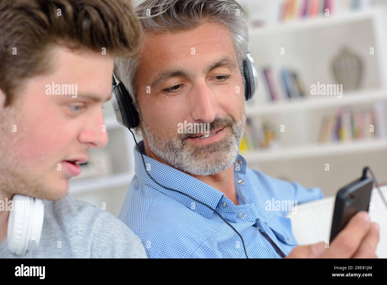 Man showing his cellphone screen to younger man Stock Photo - Alamy