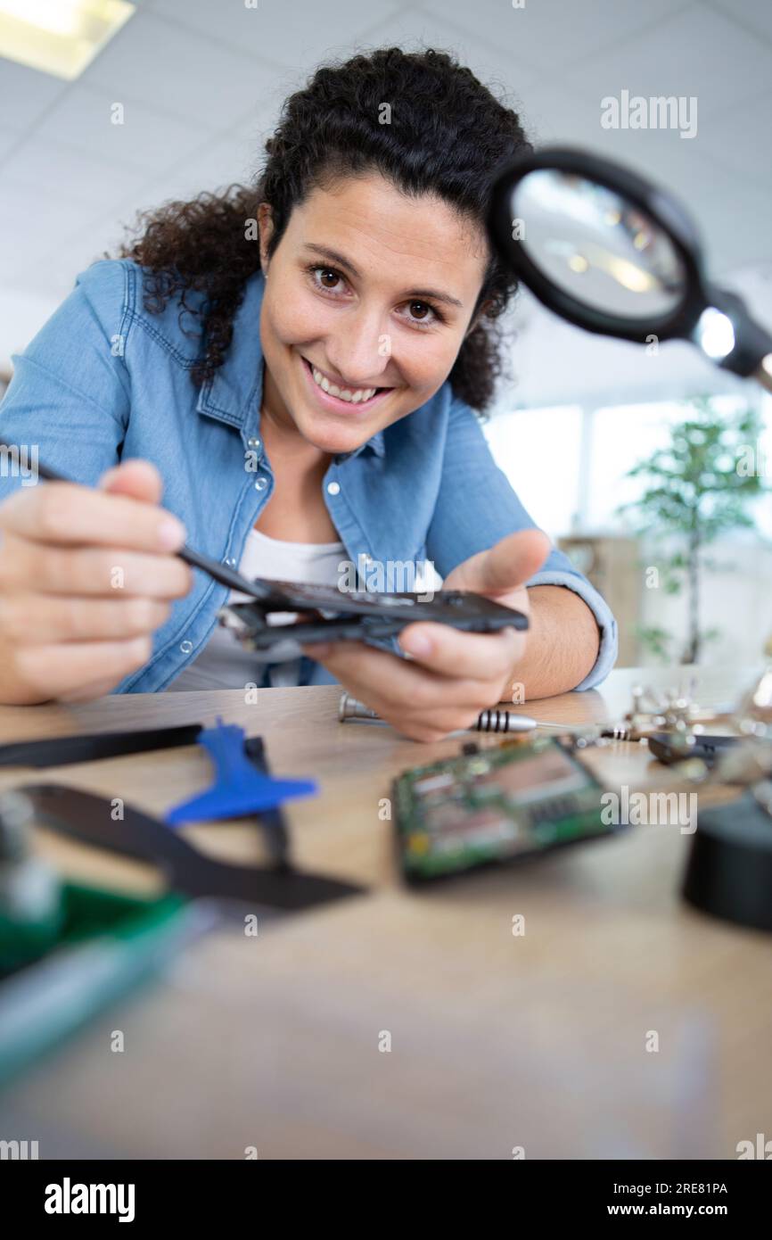 female engineer looking at circuit through magnifying glass Stock Photo ...