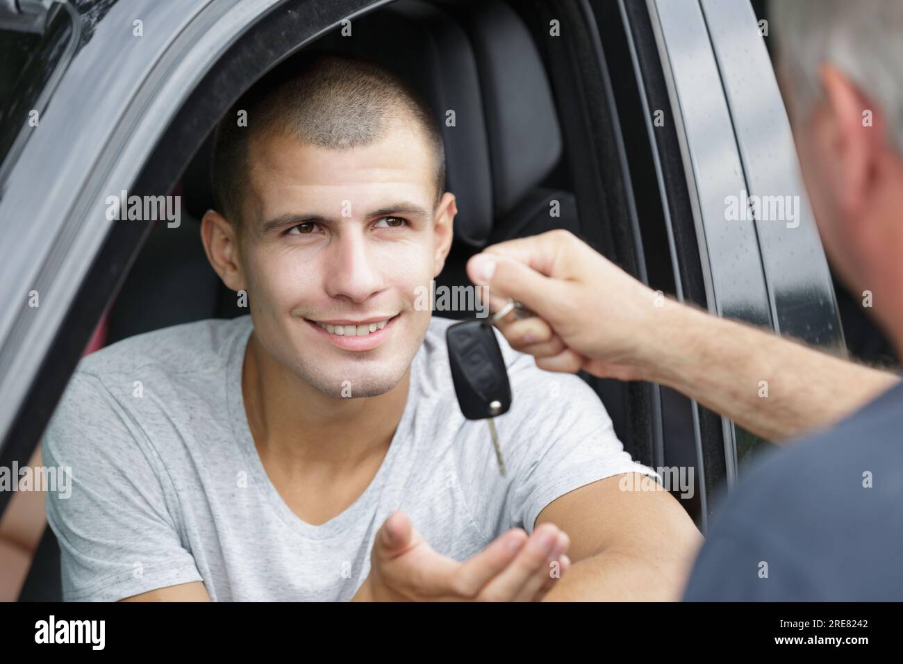 senior man giving car key to younger man Stock Photo - Alamy