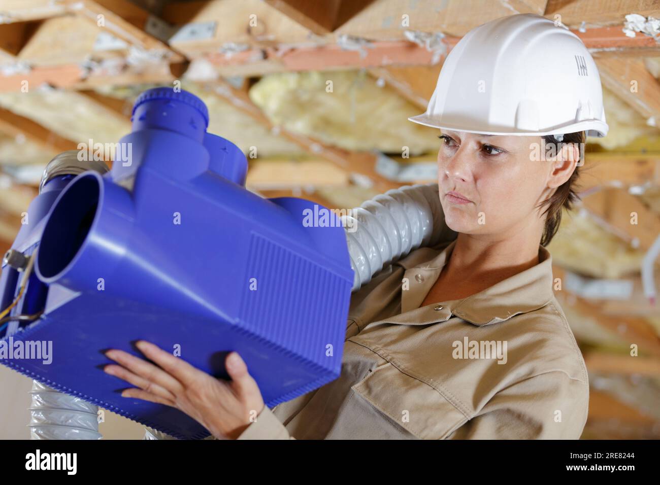 female worker fitting ventilation system in buildings ceiling Stock ...