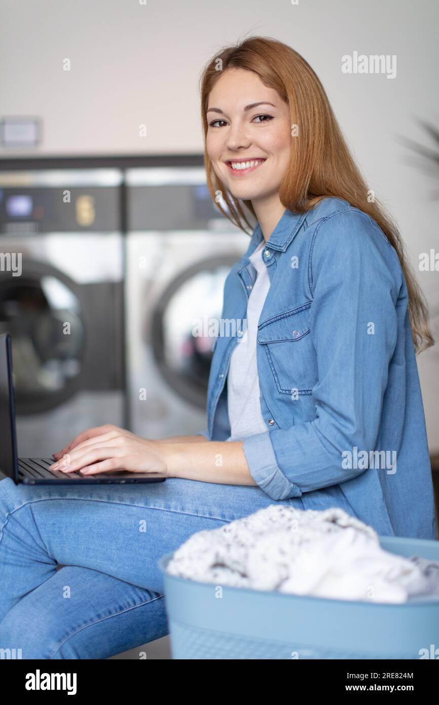 young woman using pc in laundry Stock Photo - Alamy