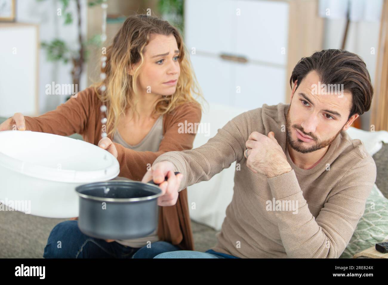 emotional young couple collecting water leaking from ceiling Stock ...