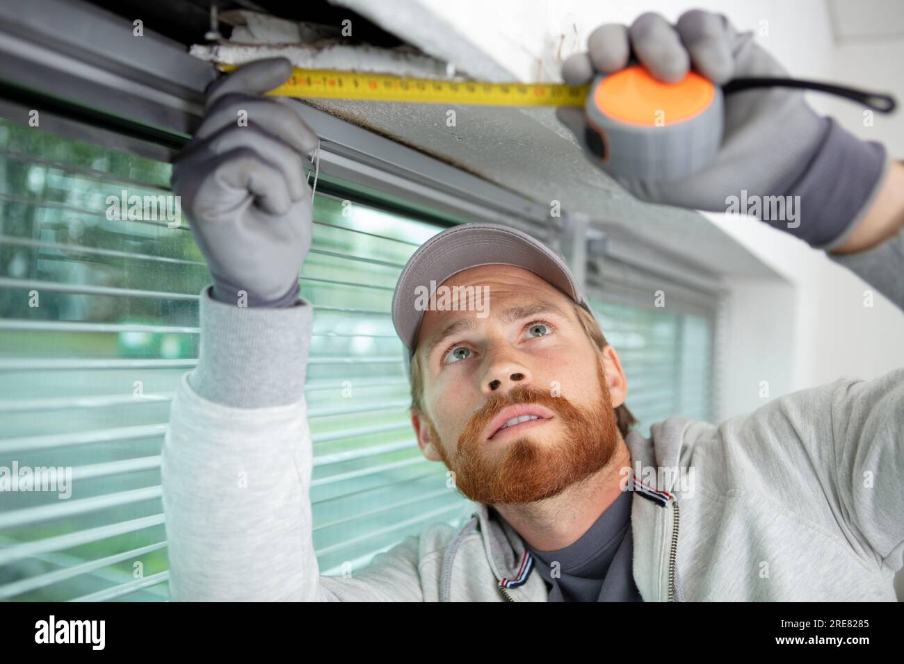 service man installing window with measure tape Stock Photo - Alamy