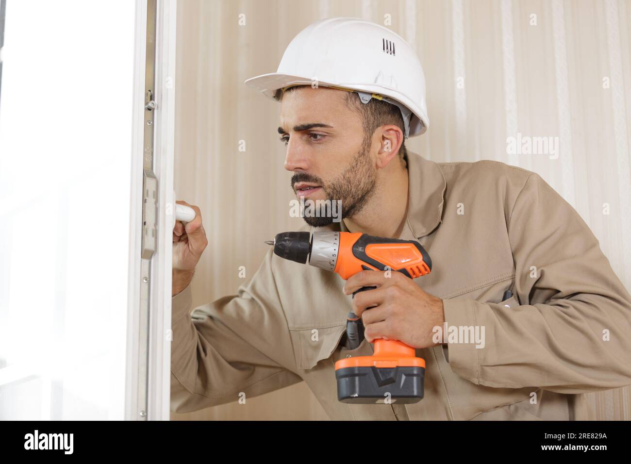 man drilling a hole in a window frame Stock Photo - Alamy