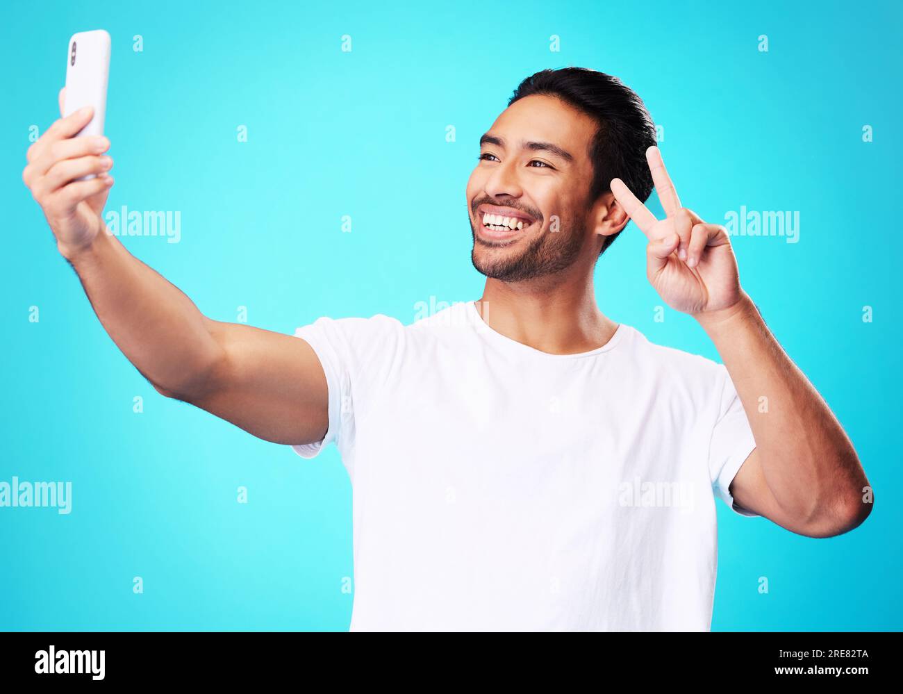 Happy, peace sign and a man with a phone on a blue background for ...