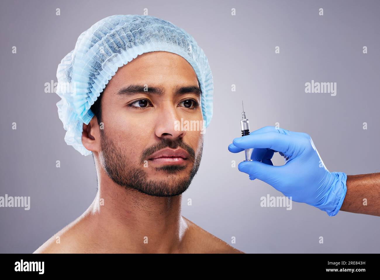 Hand, face and plastic surgery with a man in studio on a gray ...