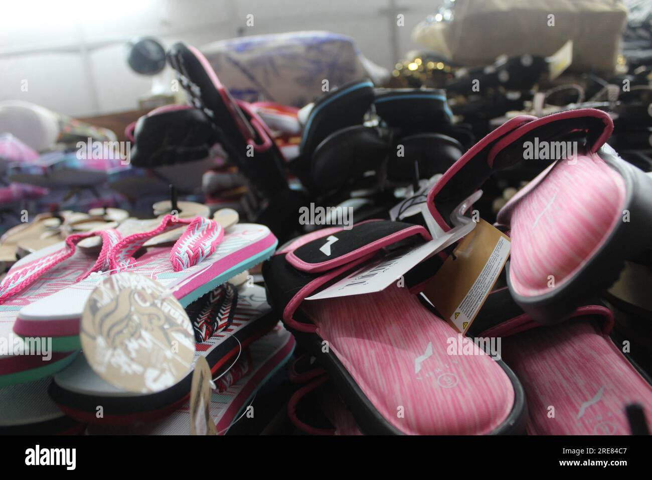 A close up upward angle shot of flip flops, sandals and sliders hanging ...