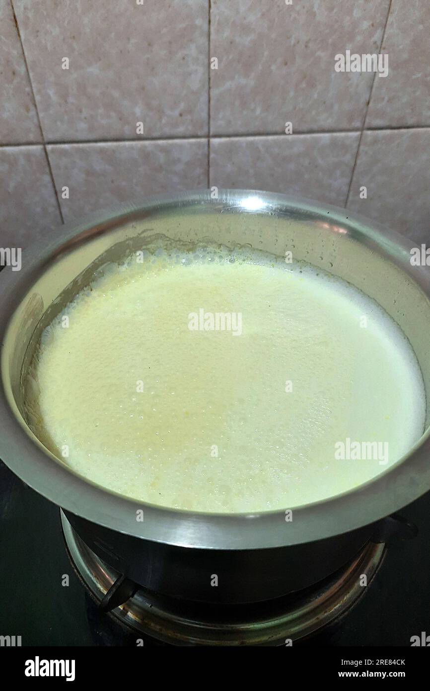 View of boiling milk in stainless steel container kept on gas stove ...