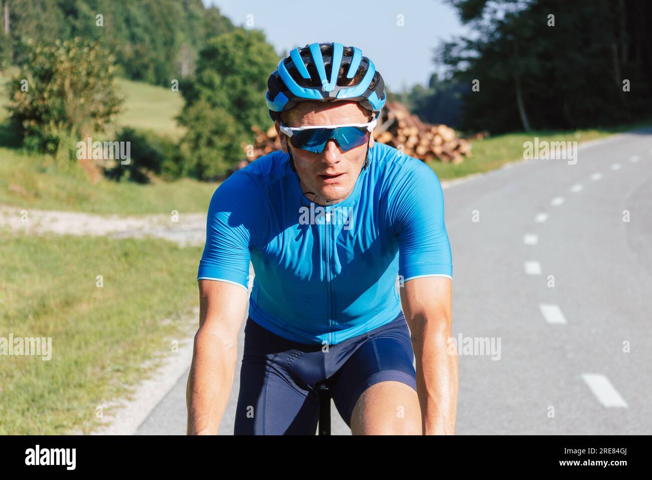 Athlete man in cycling blue jersey and gear, riding a professional ...