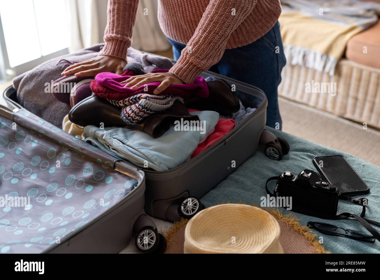 Hands of biracial woman packing suitcase in bedroom Stock Photo - Alamy