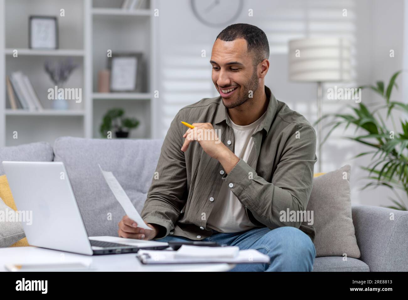 Young african american man working at home with laptop and documents ...