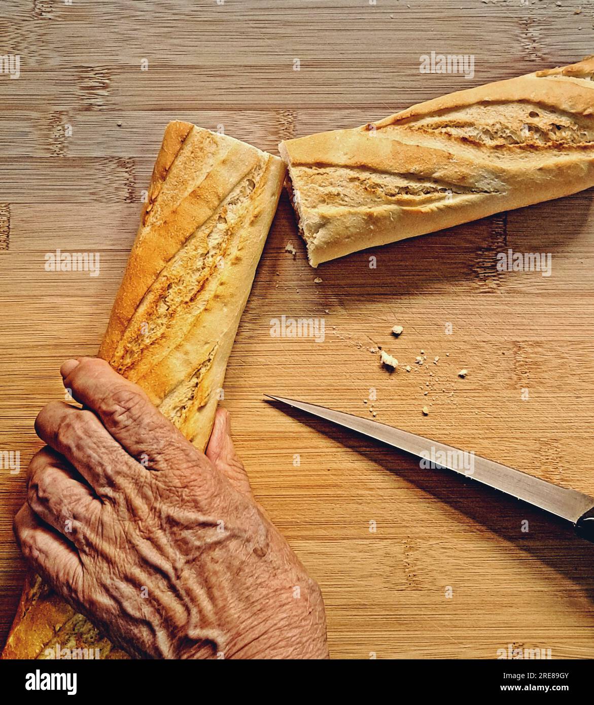 Overhead view of a woman's hand slicing a baguette Stock Photo - Alamy