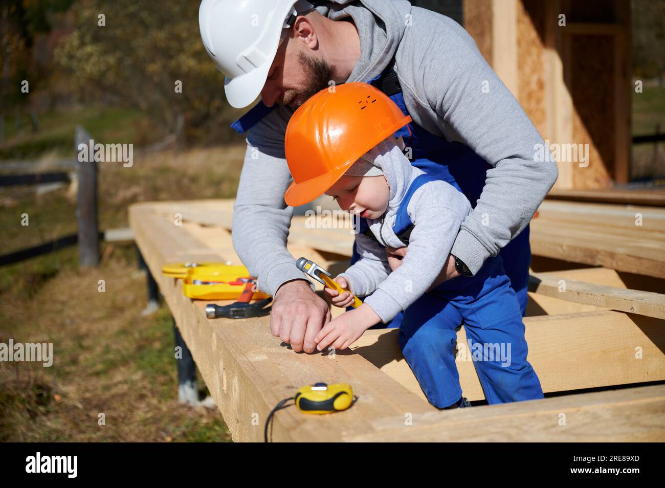 Father with toddler son building wooden frame house. Male builder ...