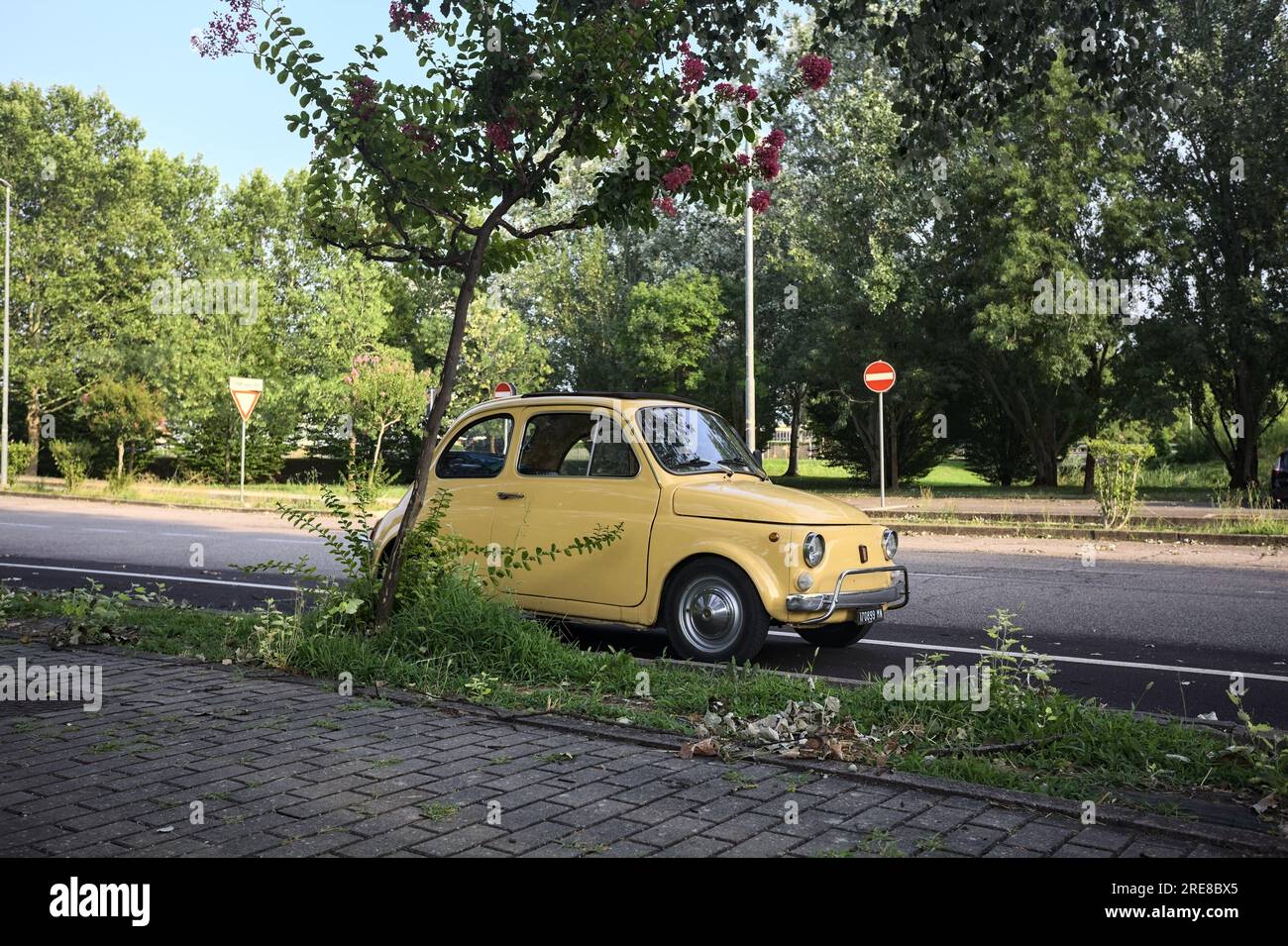 1957 Fiat 500 parked by the edge of a road next to a park at sunset ...
