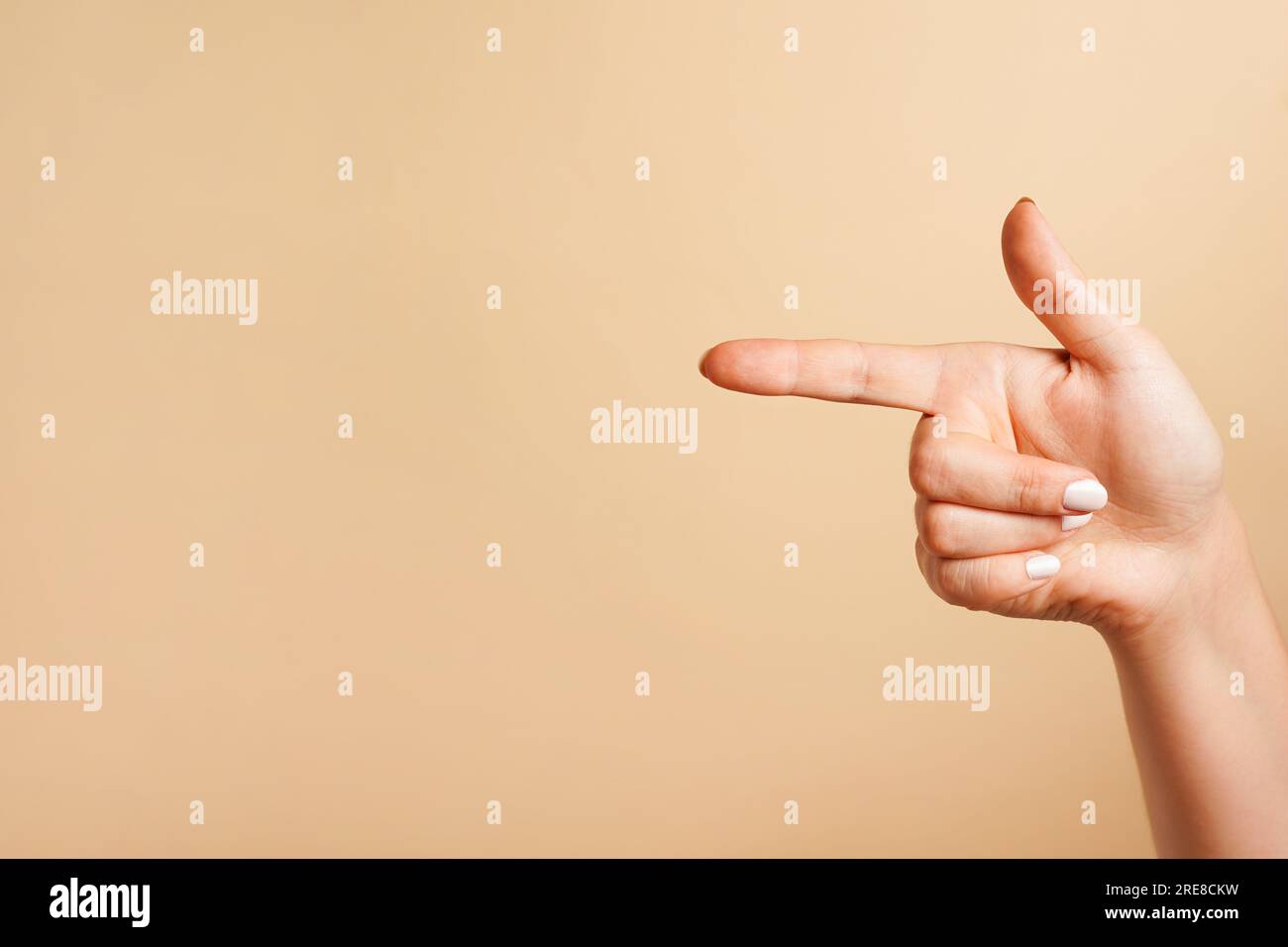 a forefinger pointing at a position, beige background with copy space ...