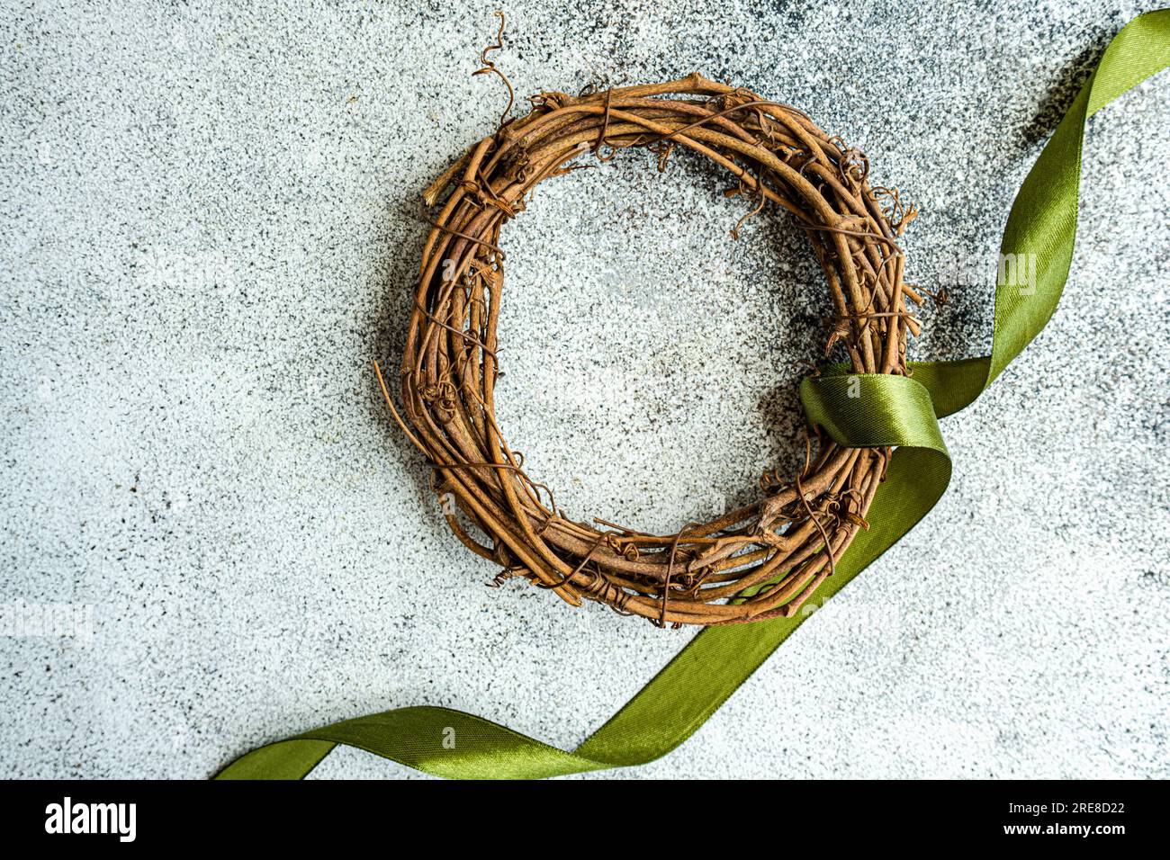 Wreath of grape vine with bright green ribbon on concrete background ...