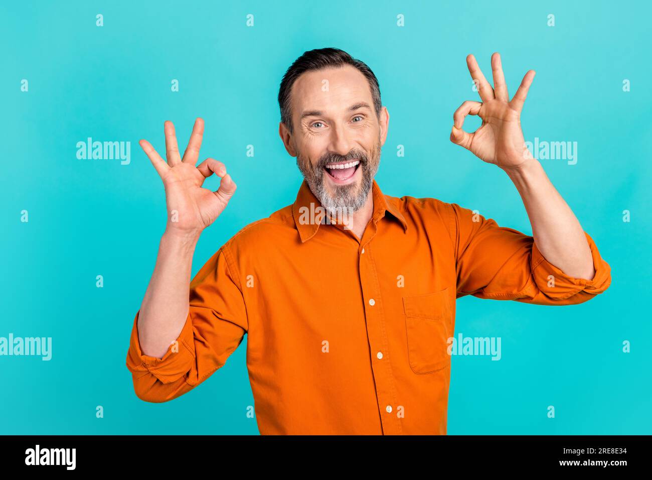 Photo of charming excited man dressed orange shirt showing two okey ...