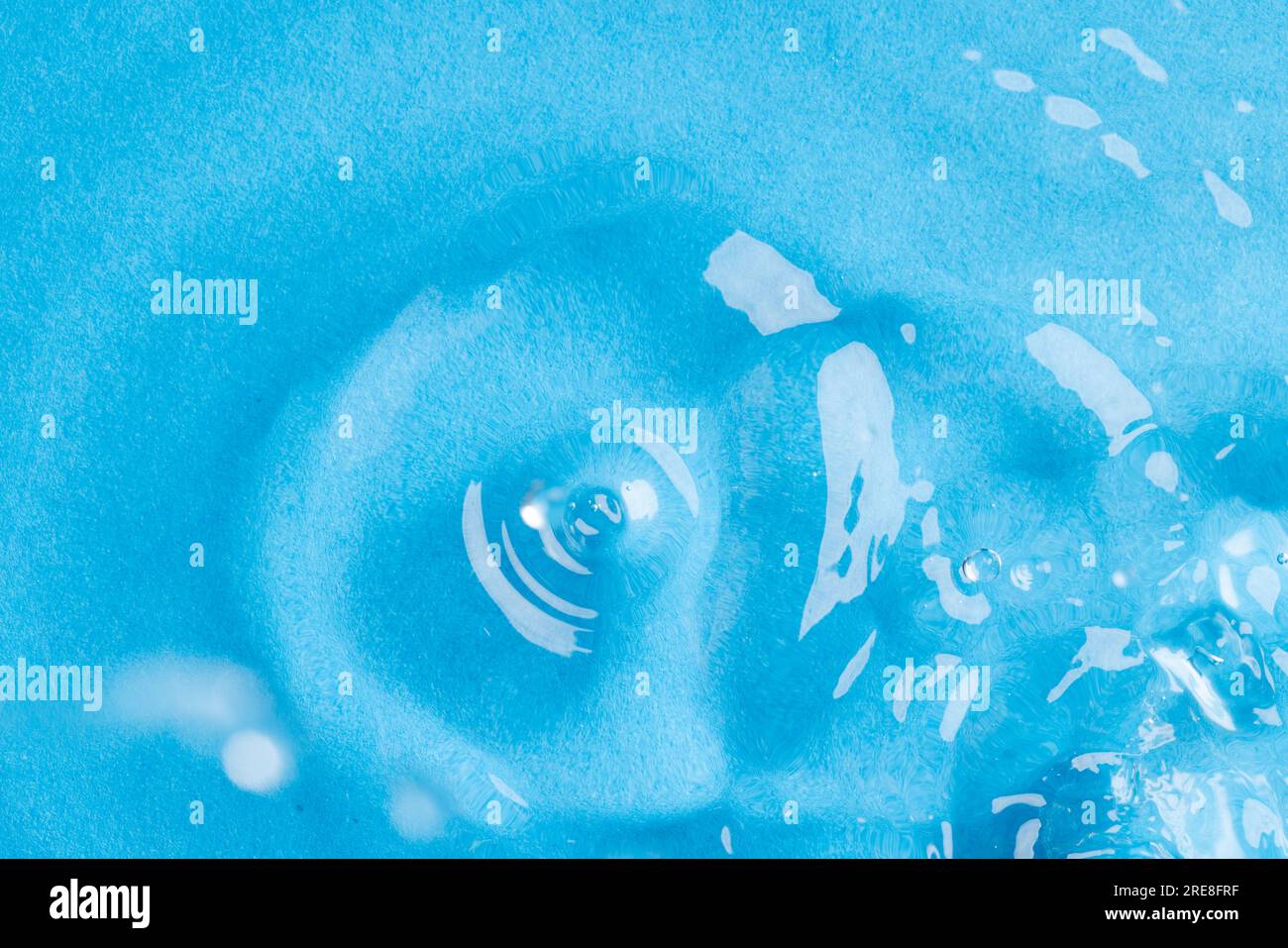 Close up of water drop falling into water with ripples and copy space ...