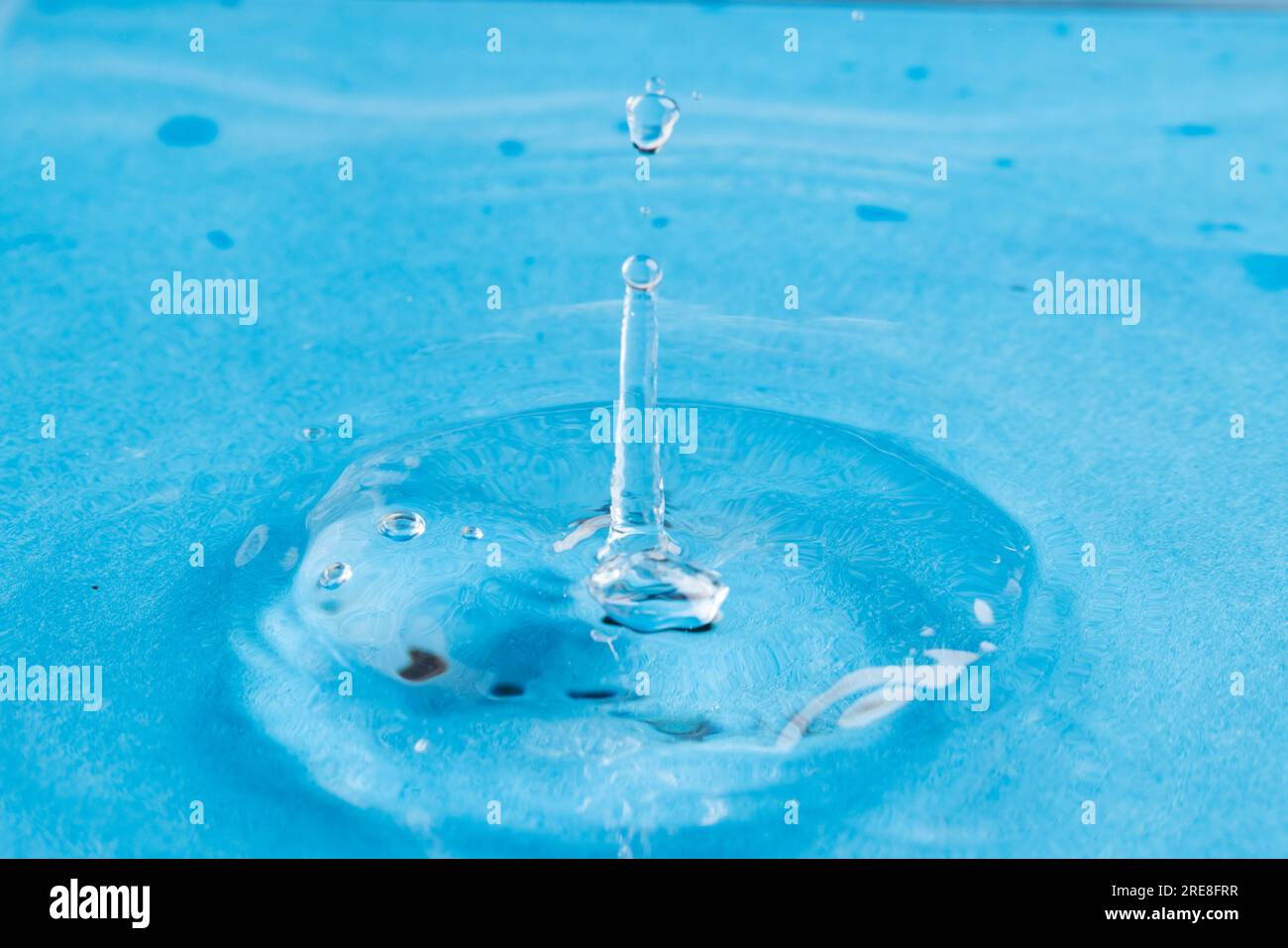 Close up of water drop falling into water with ripples and copy space ...