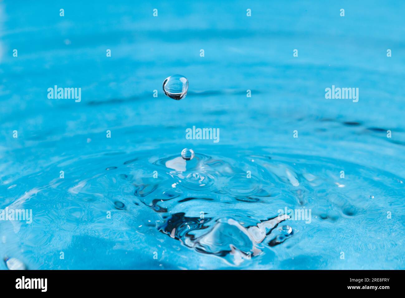 Close up of water drop falling into water with ripples and copy space ...