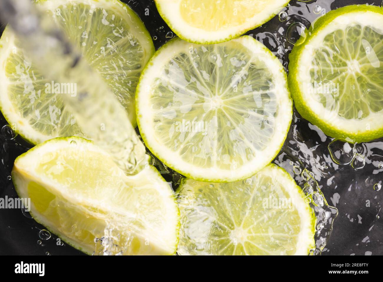 Close up of sliced lemons and limes in water with copy space on black ...