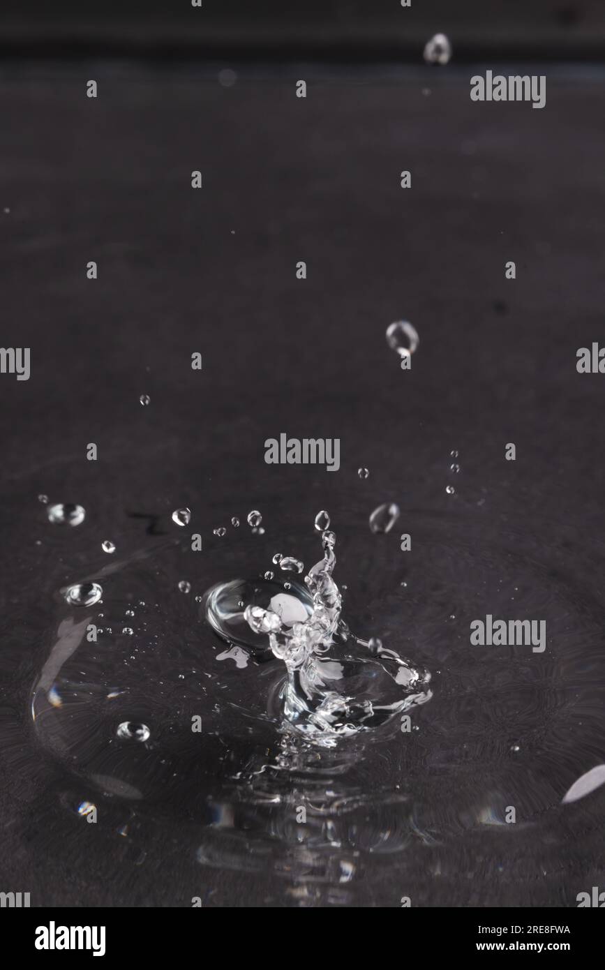 Close up of water drop falling into water with ripples and copy space ...