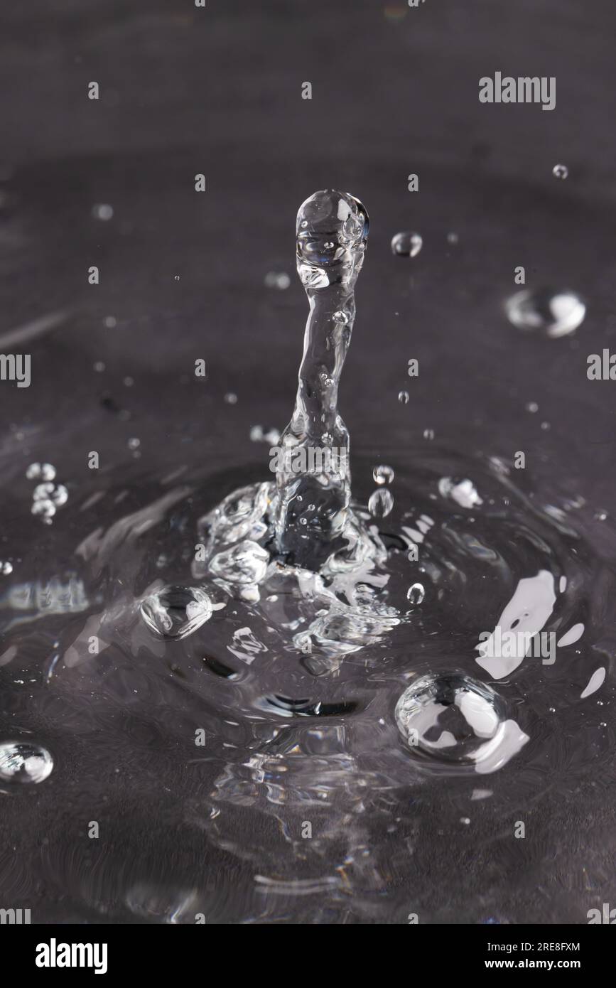 Close up of water drop falling into water with ripples and copy space ...