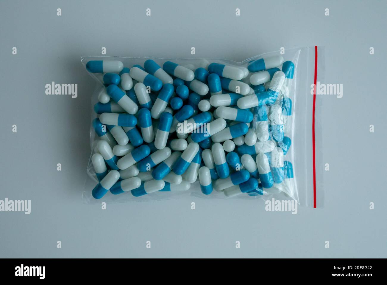Several white-blue capsules in a ziplock bag against a white background ...