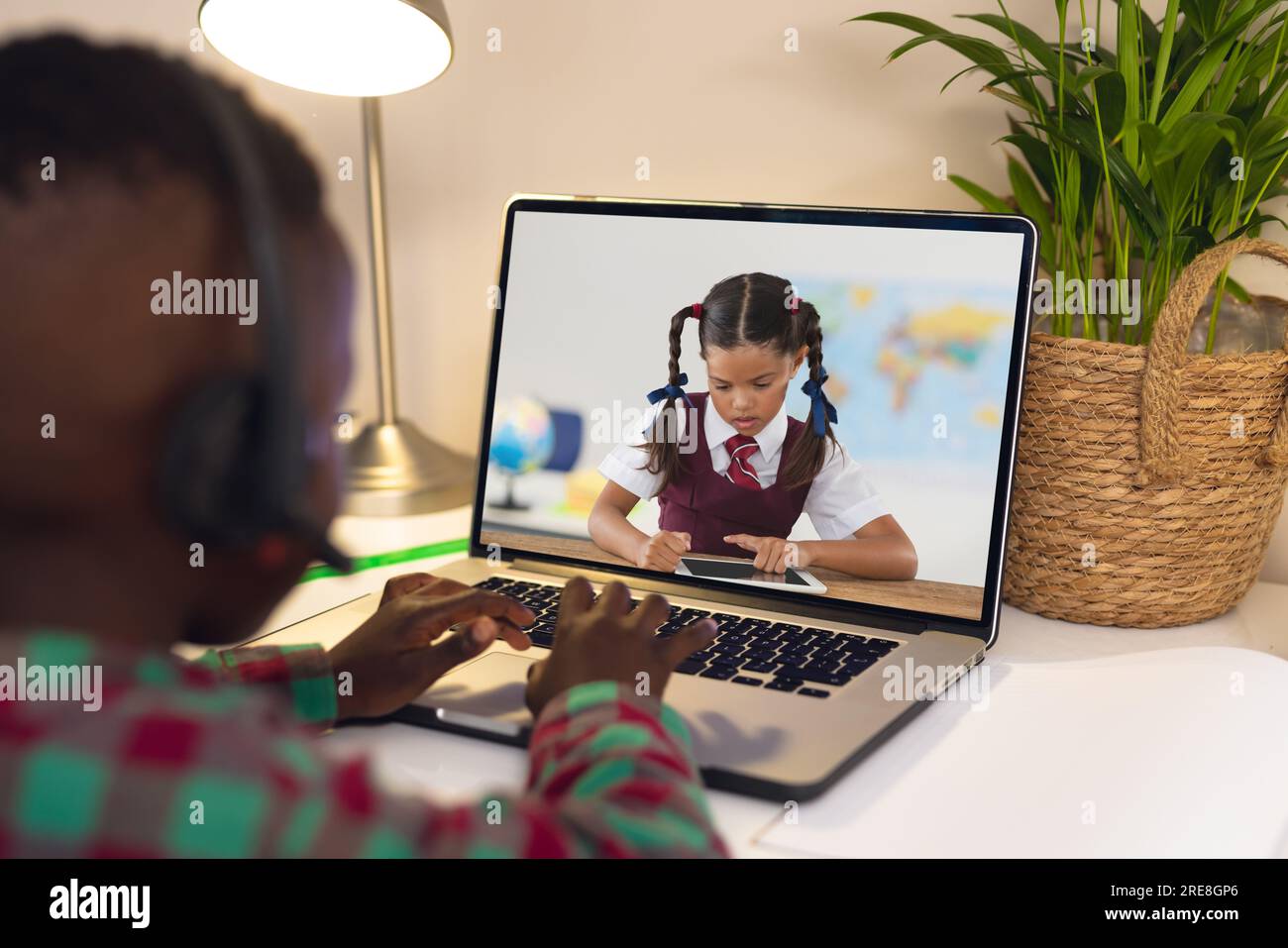 Rear view of african american boy using laptop while having a video call with biracial girl ...