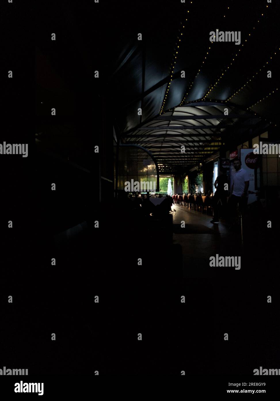 Aisle between tables that leads to a garden in a restaurant at dusk ...