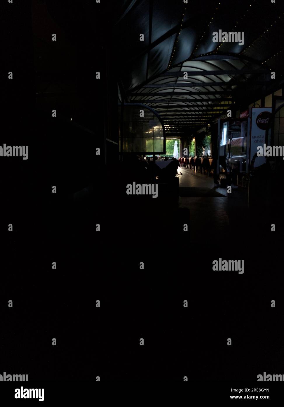 Aisle between tables that leads to a garden in a restaurant at dusk ...