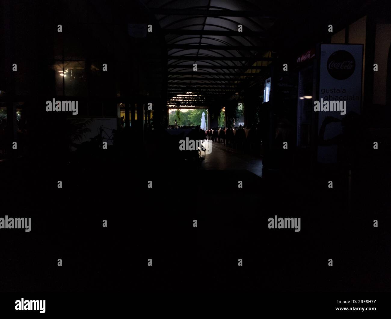 Aisle between tables that leads to a garden in a restaurant at dusk ...