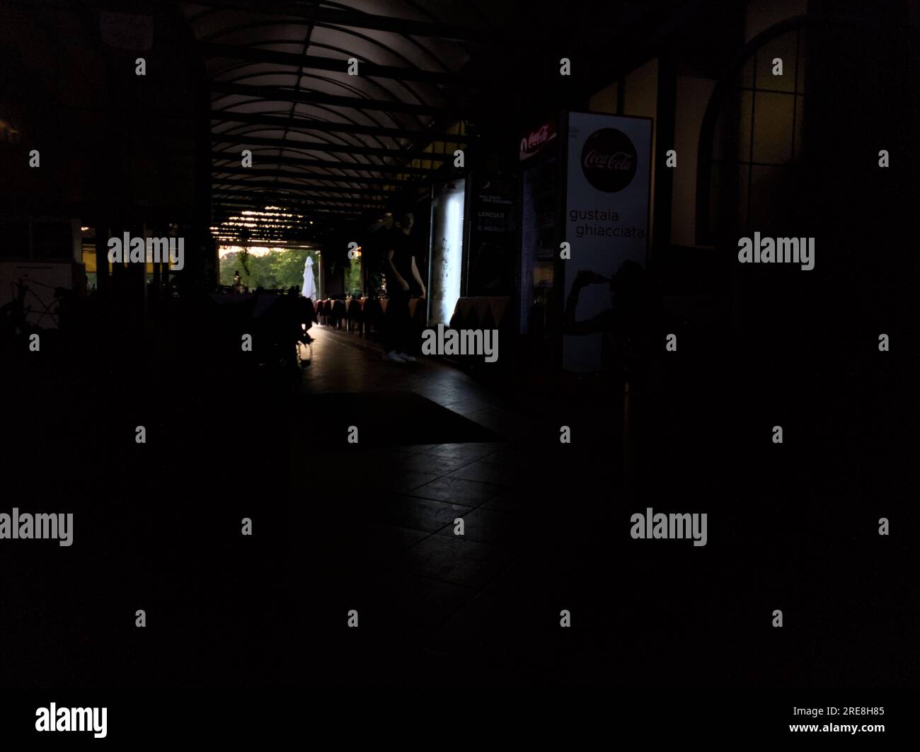 Aisle between tables that leads to a garden in a restaurant at dusk ...