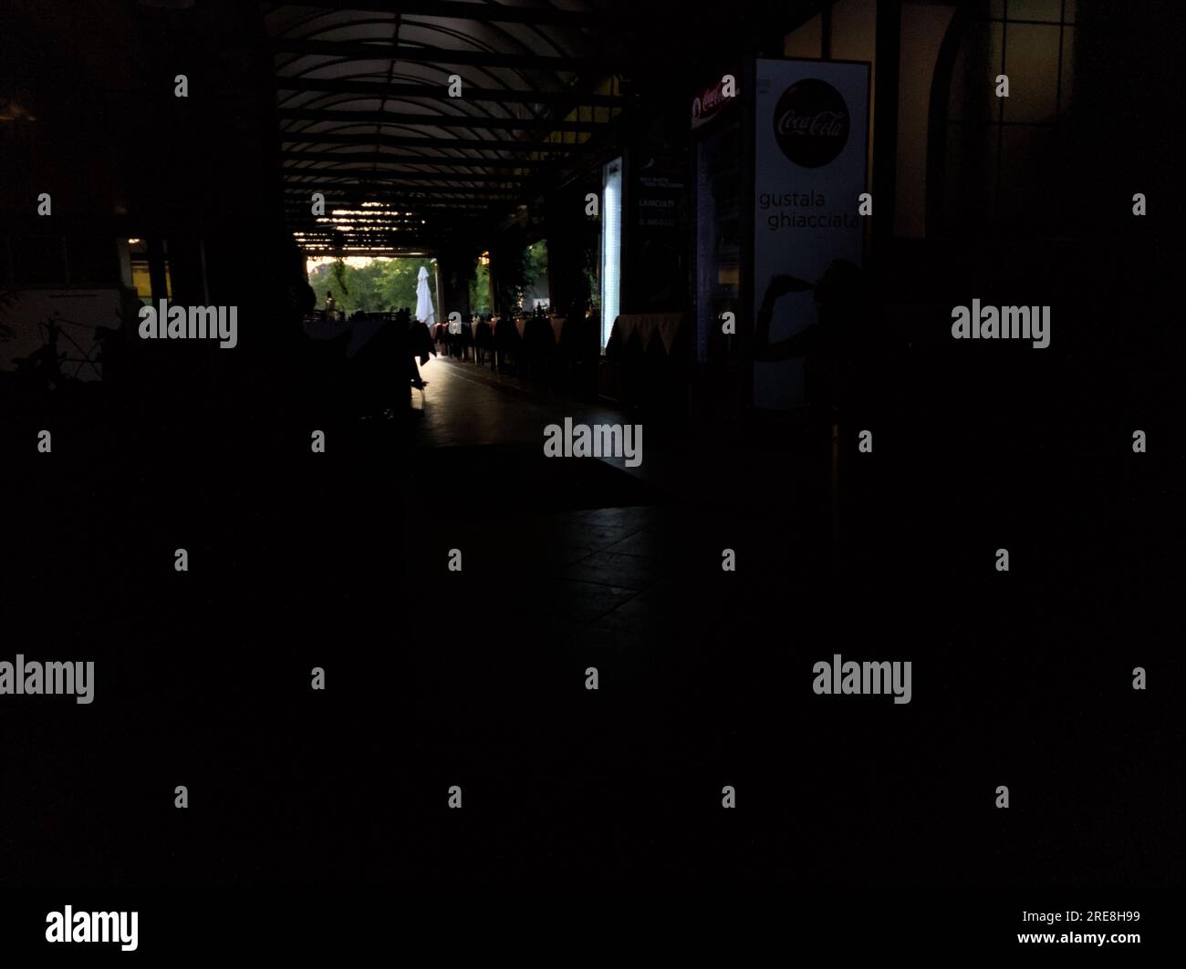 Aisle between tables that leads to a garden in a restaurant at dusk ...