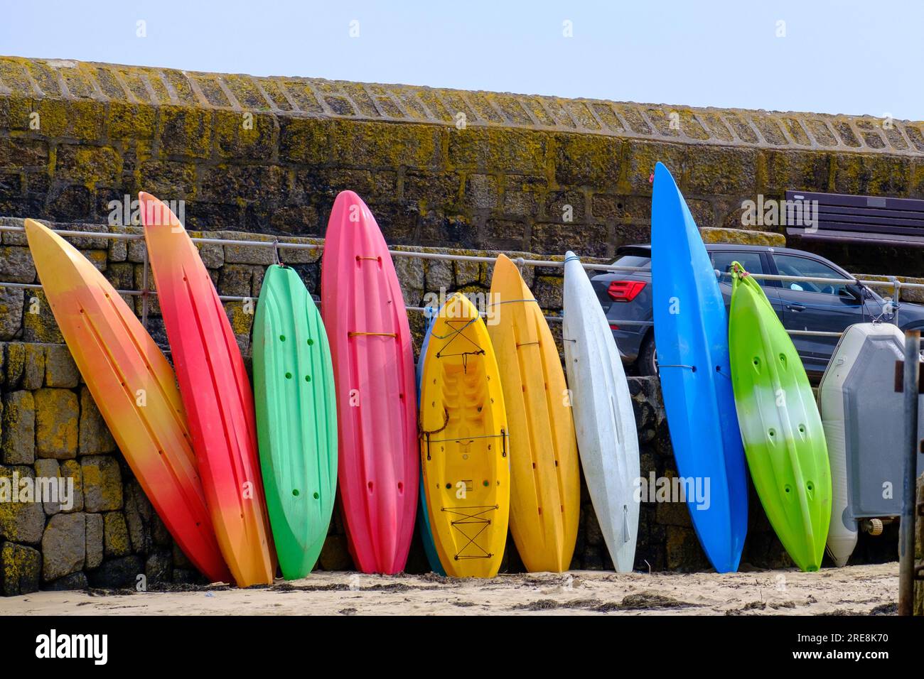 Colourful surfboards lean against stone wall at harbour, Mousehole ...