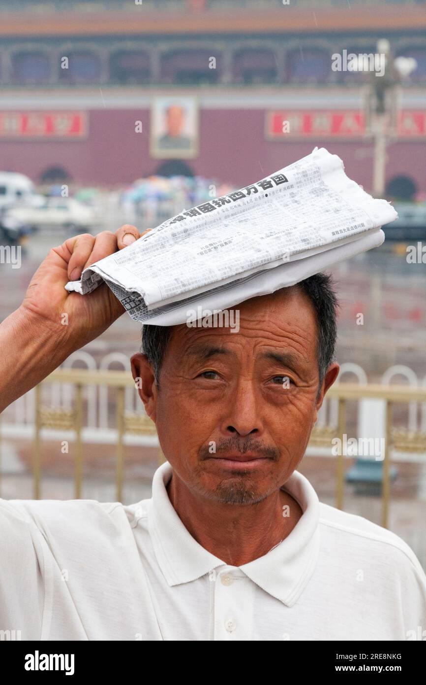 Chinese tourist protecting himself from rain with folded newspaper on a ...