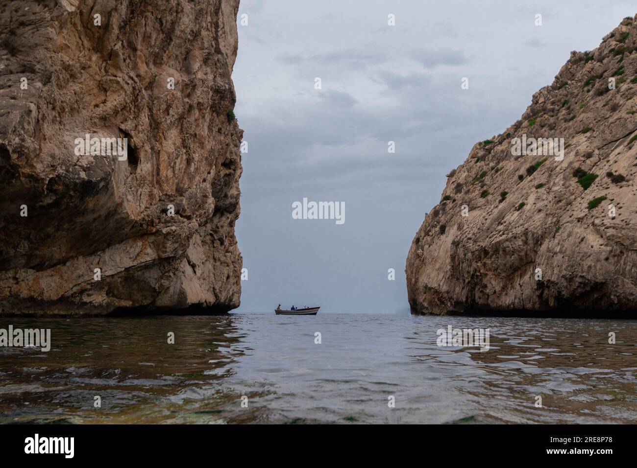 A boat on a beach between two large rocky mountains, in one of the ...