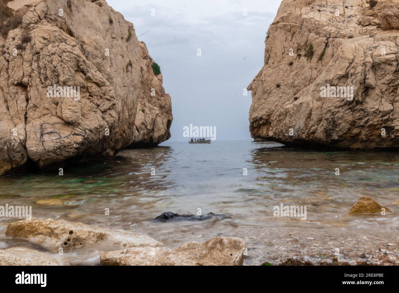 A boat on a beach between two large rocky mountains, in one of the ...