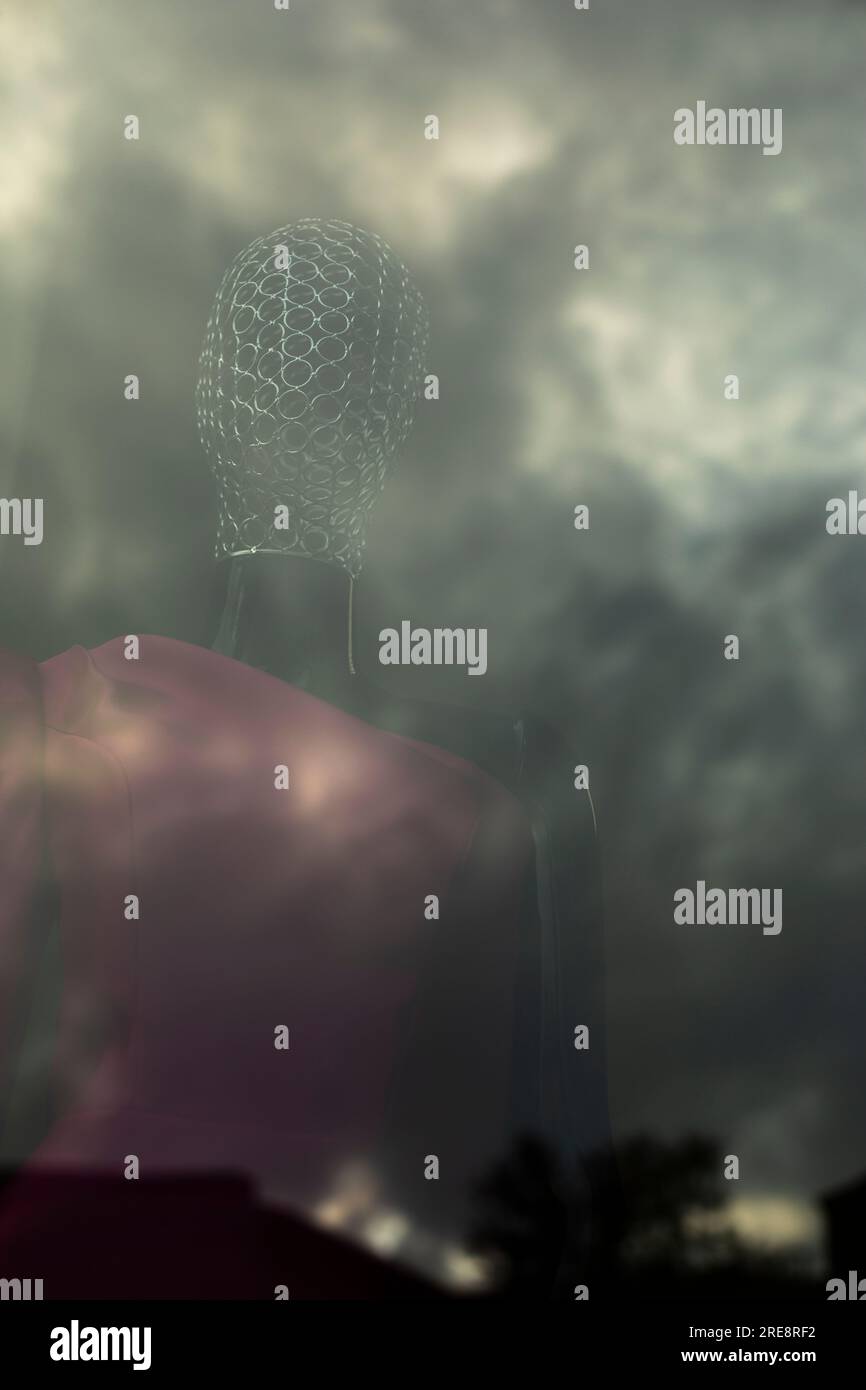 Sculpture behind glass. Reflection of clouds in glass. Figure without ...