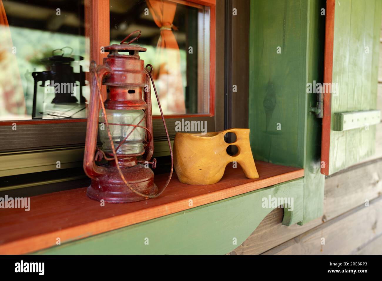 Traditional Finnish wooden mug kuksa and vintage lantern on the window ...