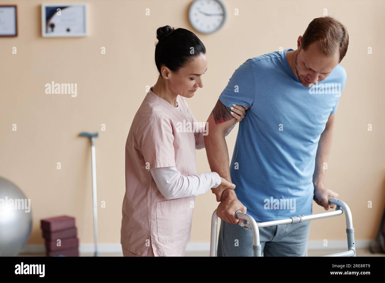 Doctor helping patient to walk with walker during his rehabilitation in ...