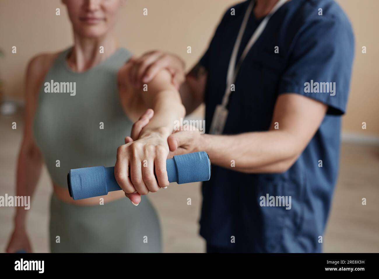 Close-up of patient training with dumbbells together with therapist in ...