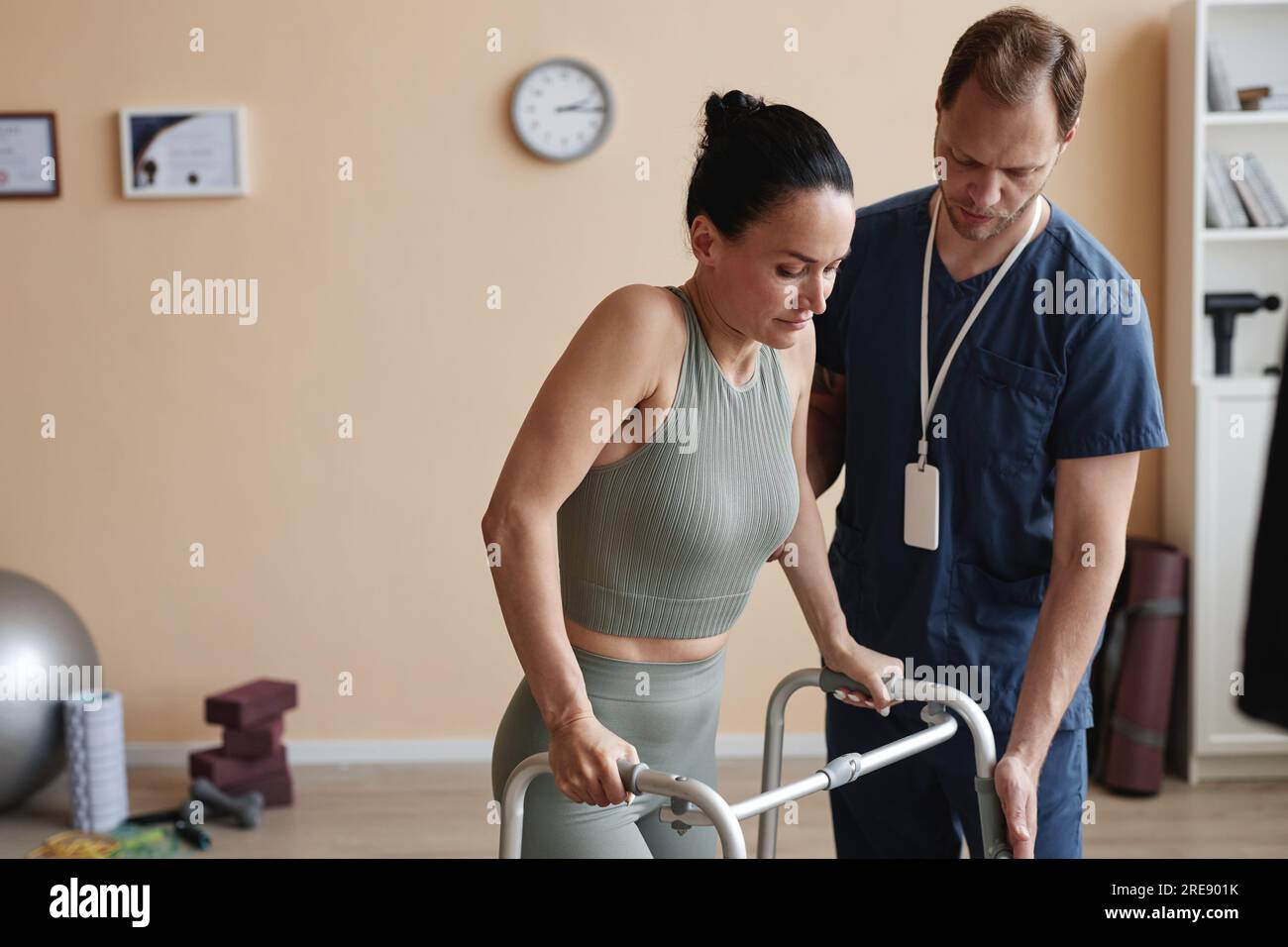 Doctor helping patient to walk using walker during rehabilitation in ...