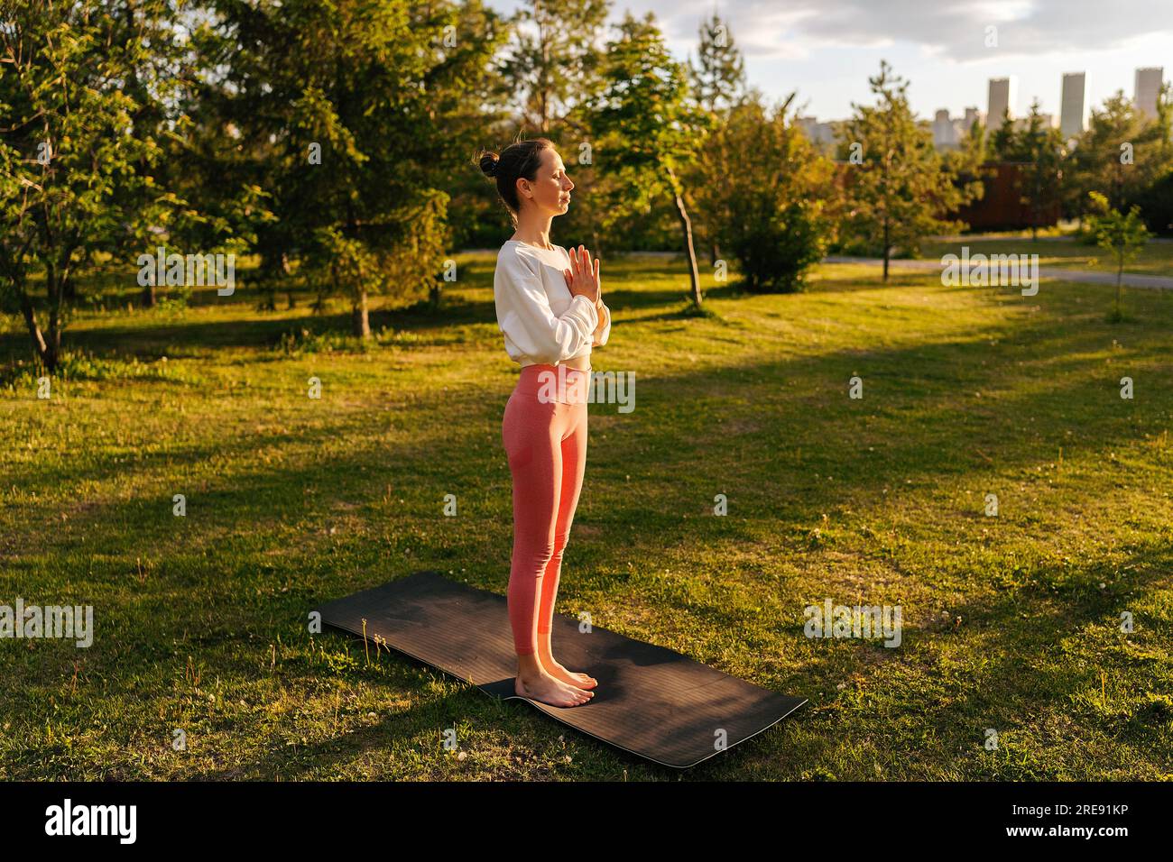 Side view of meditate young woman standing on yoga mat with closed eyes ...
