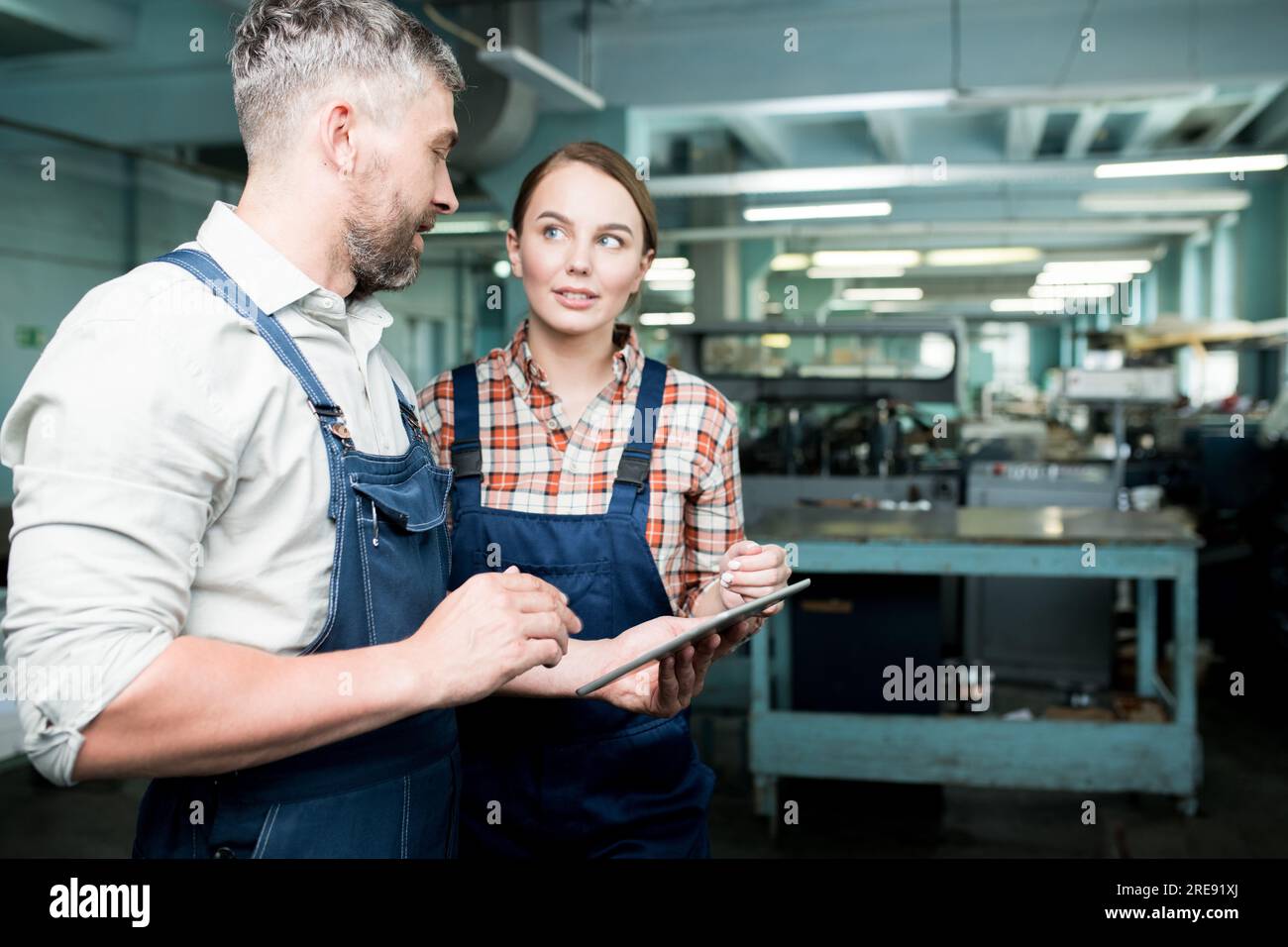 Confident modern industrial workers in overalls standing in factory ...