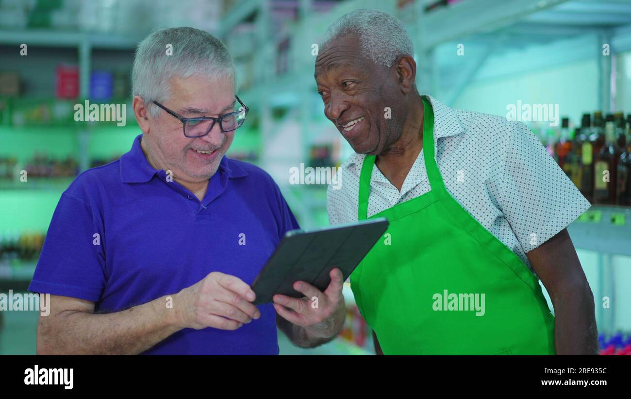 Senior manager showing tablet screen to older African American employee ...